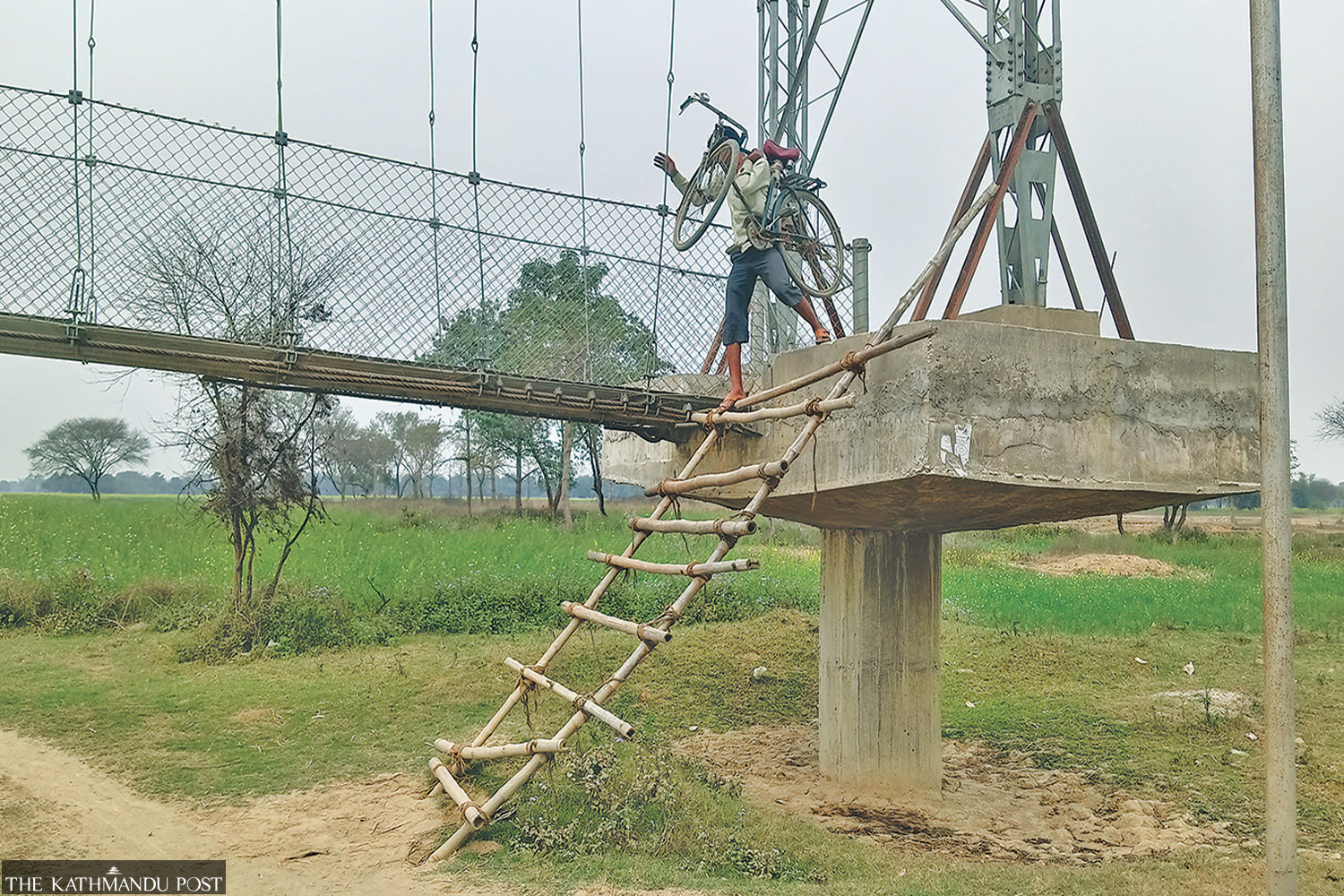 With no approach road, people use bamboo ladders to access bridge